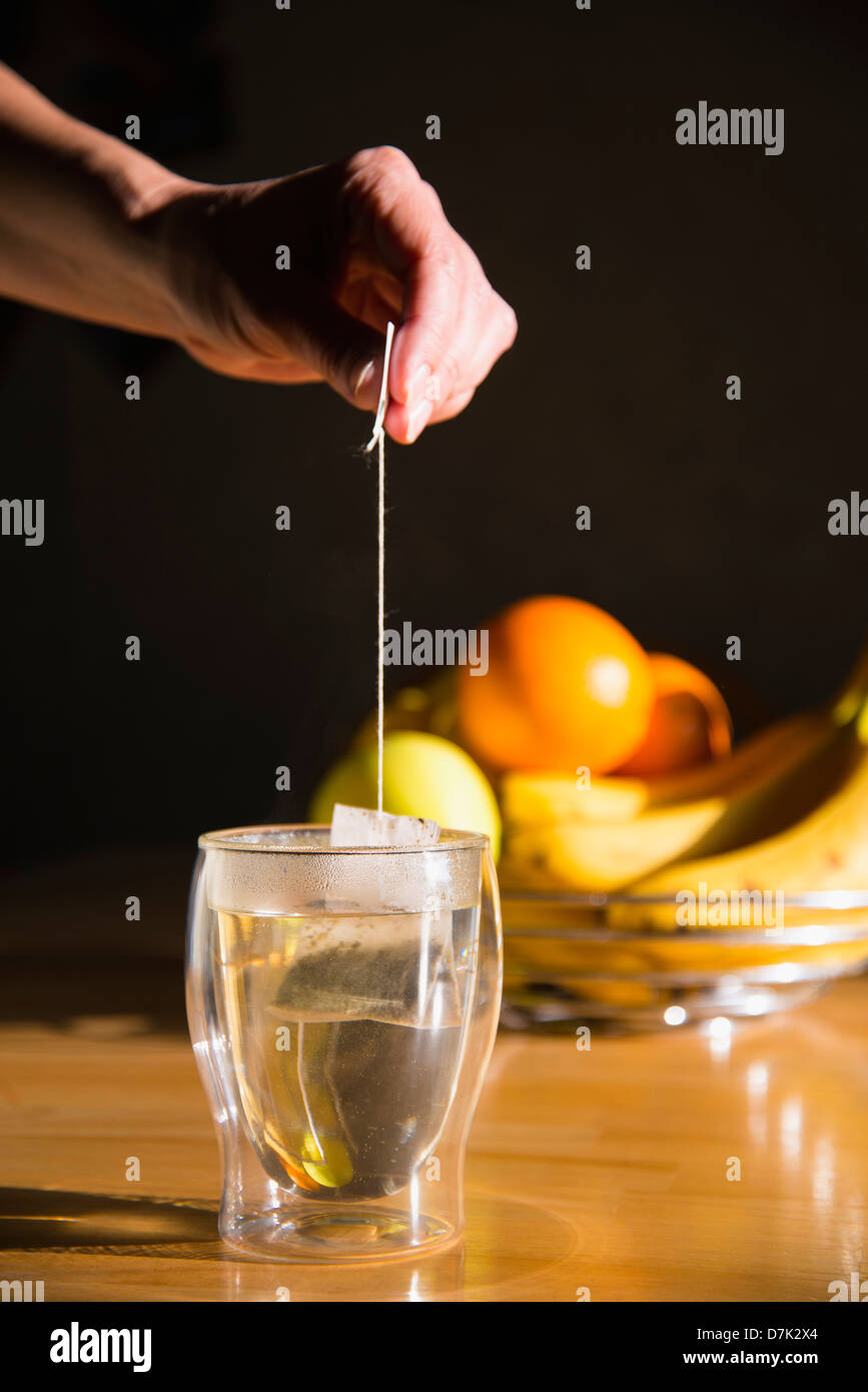 Human hand preparing tea, bowl of fruits in background Stock Photo - Alamy