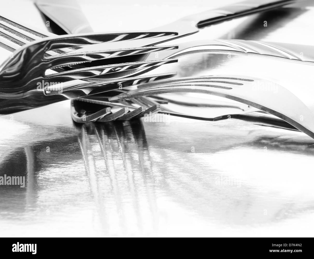 Group of forks with their tines intertwined with reflection on a shiny ...