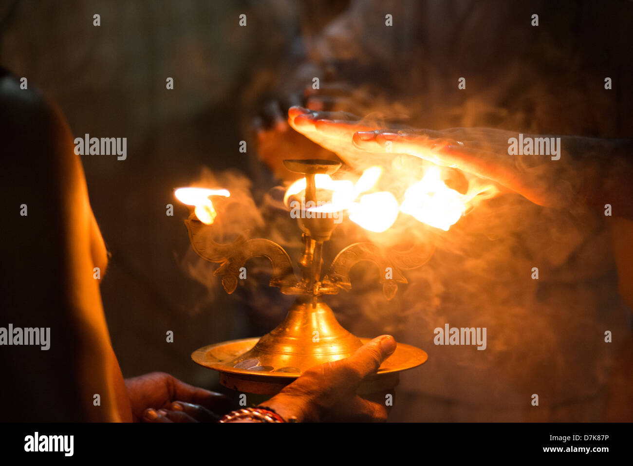 Hindu devotees pass their hands through a sacred flame at the ...