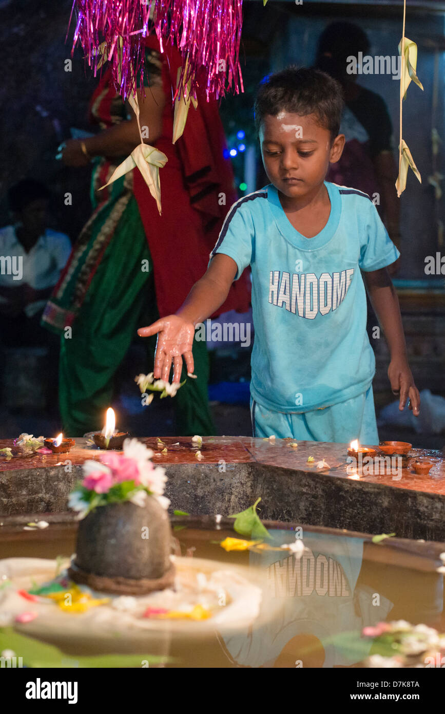 A Hindu child makes an offering of jasmine flowers at a shrine in the ...