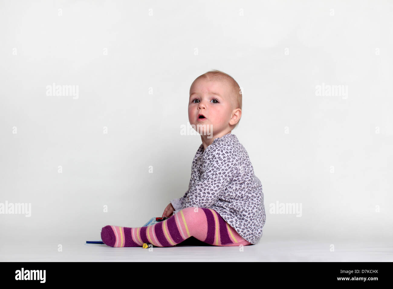 Baby girl sitting on white background Stock Photo - Alamy