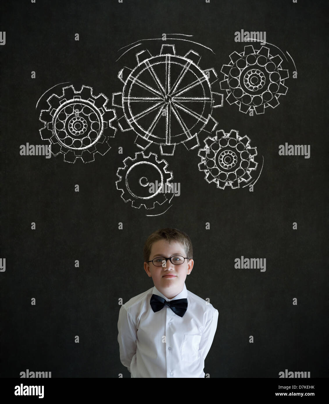 Thinking boy dressed up as business man with chalk turning gear cogs or ...