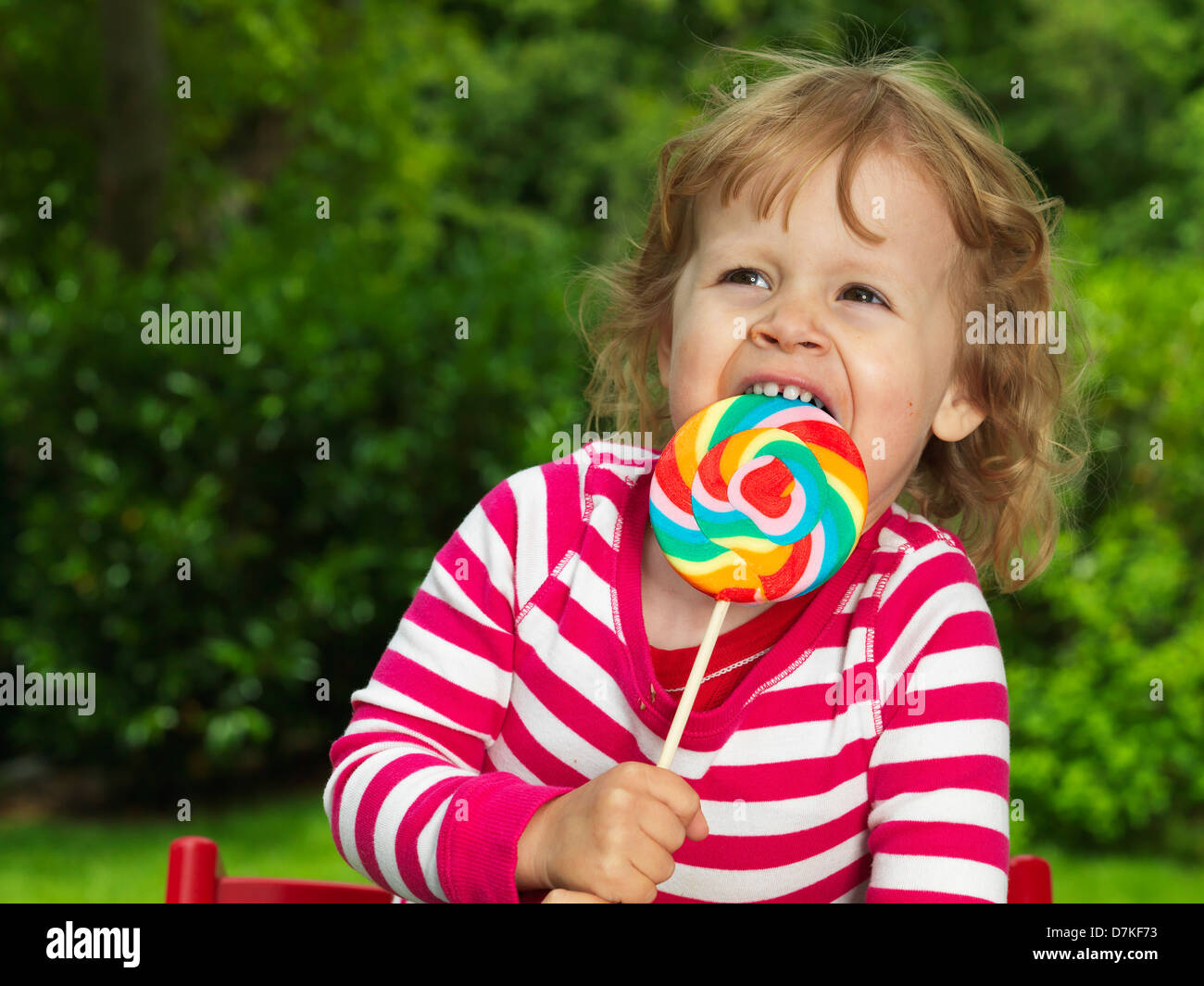 Germany, Duesseldorf, Girl sitting outside and eating lollipop Stock ...