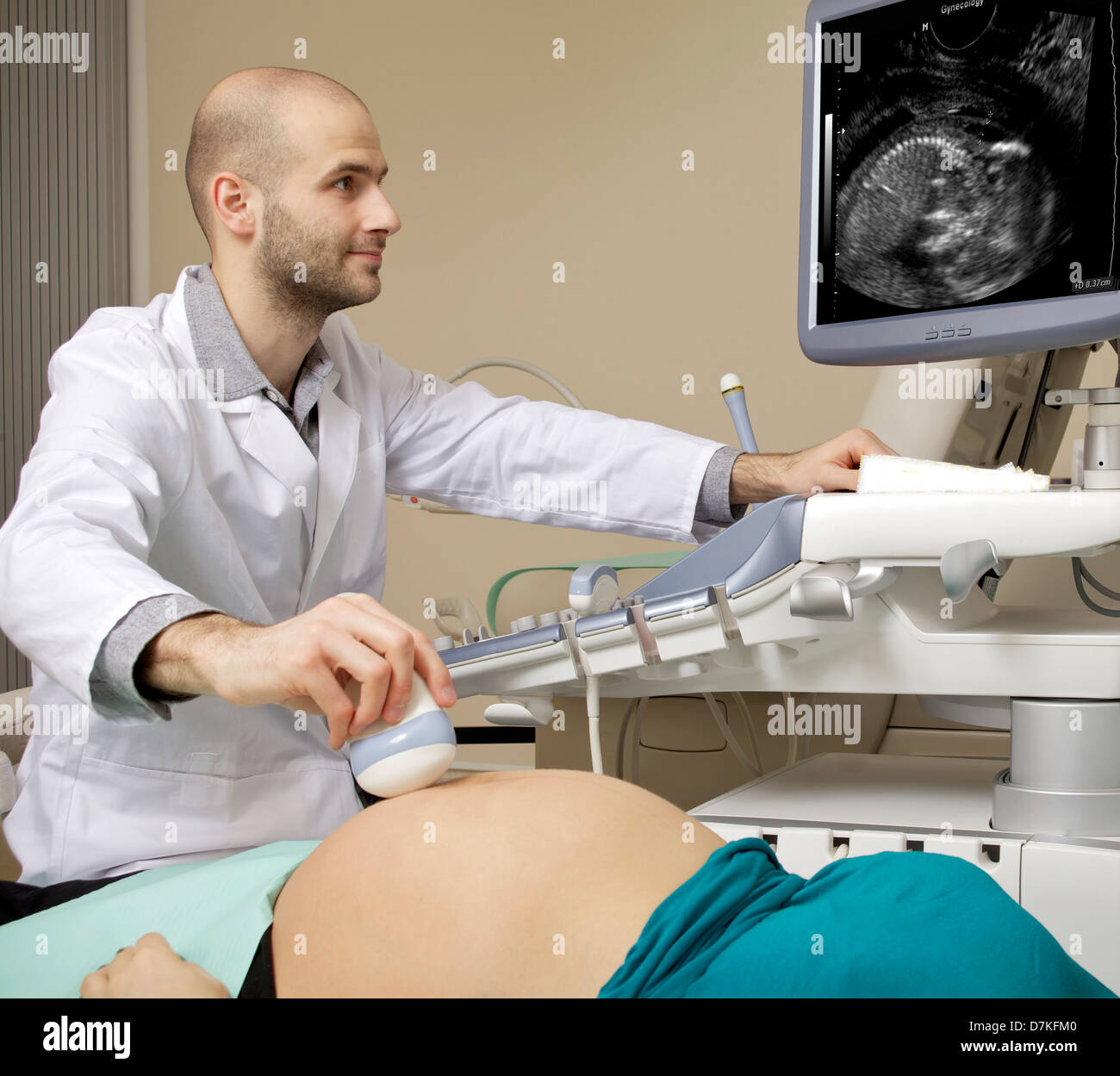Portrait of young male technician operating ultrasound machine in white ...