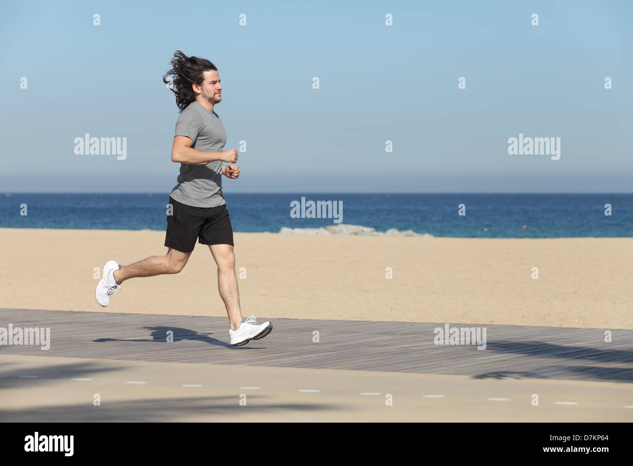 Man running on the seafront of the beach with the sea in the background ...