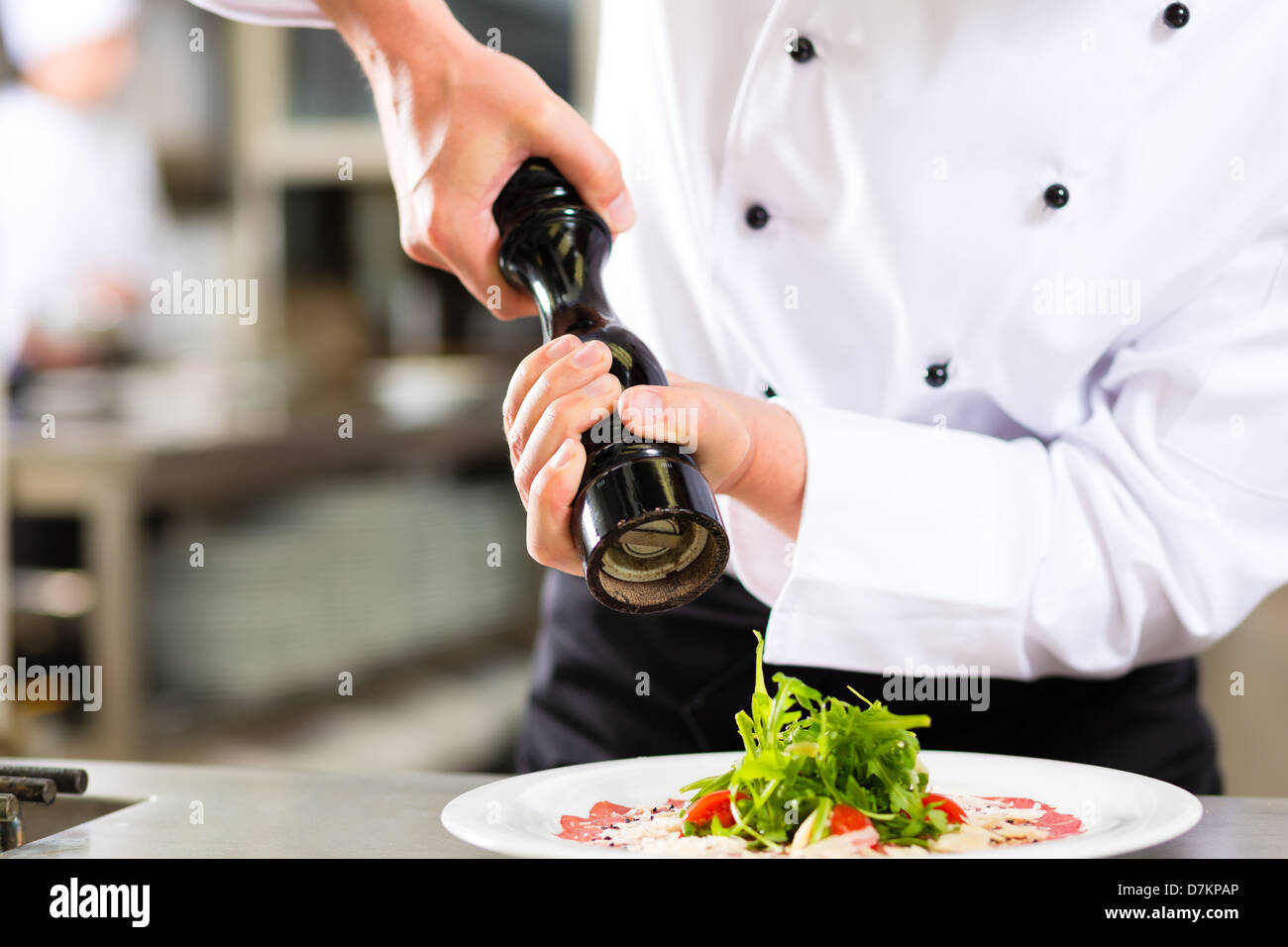 Chef in hotel or restaurant kitchen cooking, only hands to be seen, he ...