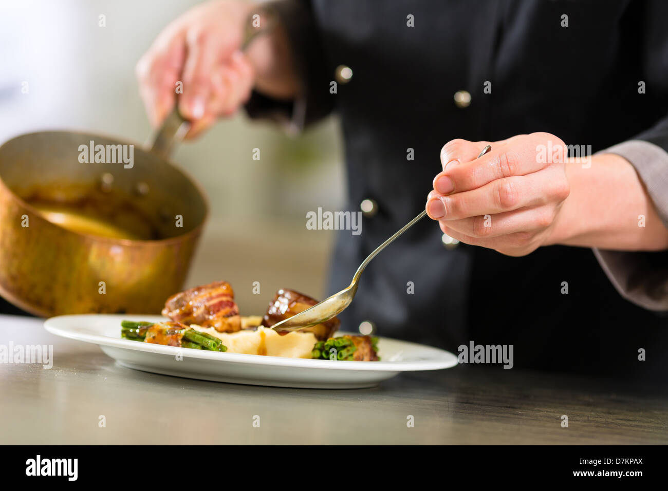 Chef in hotel or restaurant kitchen cooking, only hands to be seen, he ...