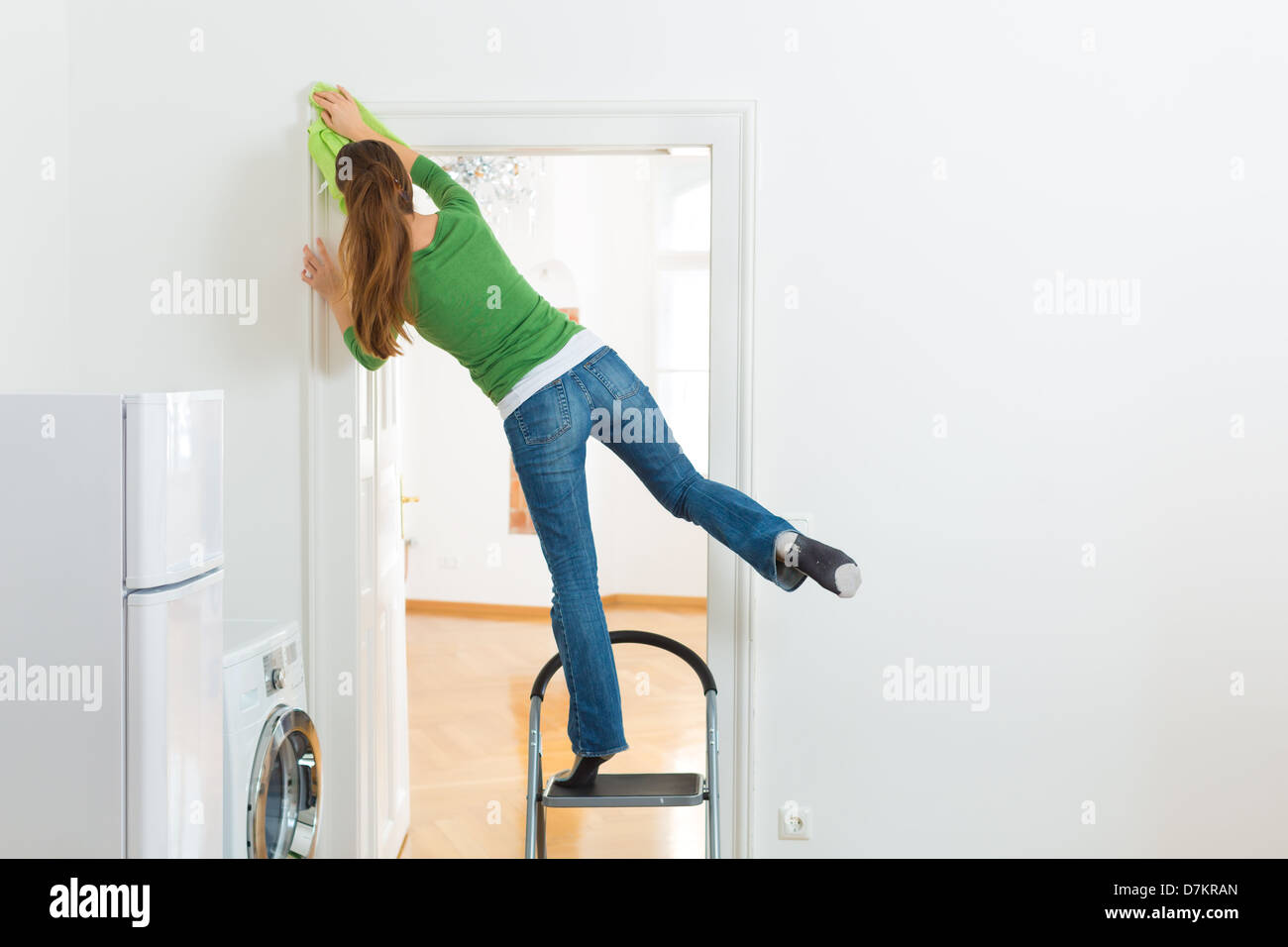 Young woman cleaning at home, she has a cleaning day and using a duster ...