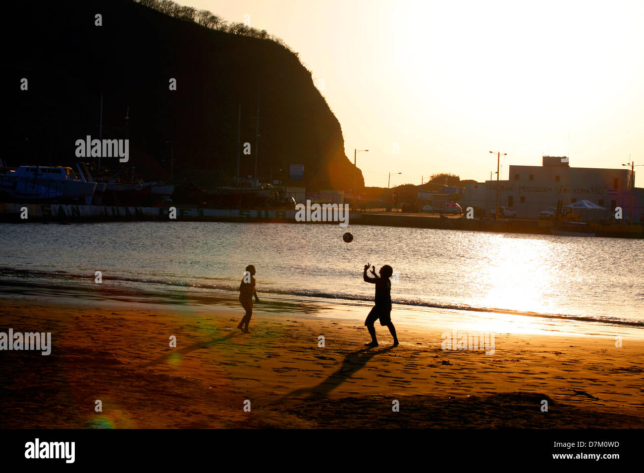 Two people play with a ball at sunset on the beach in San Juan del Sur ...