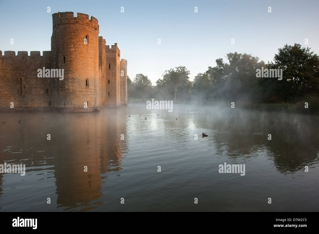 Beautiful medieval castle and moat at sunrise with mist over moat and ...