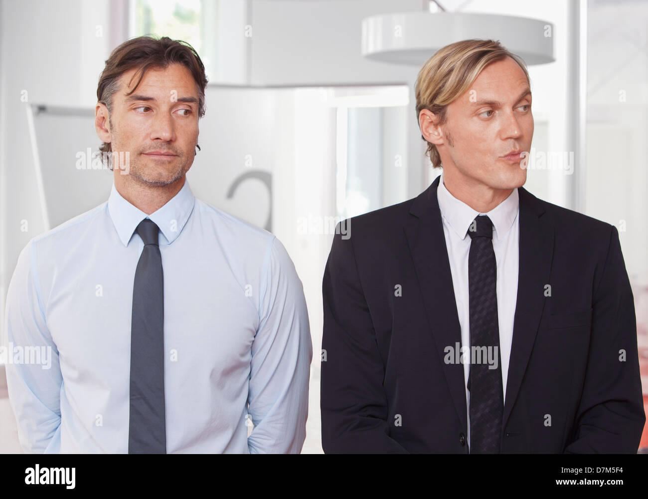 Two businessmen standing with distrust expression Stock Photo - Alamy