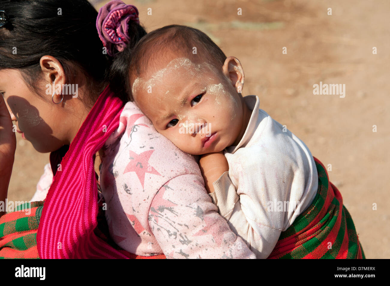 Tribal baby boy looking at the camera held in a papoose on his mother's ...