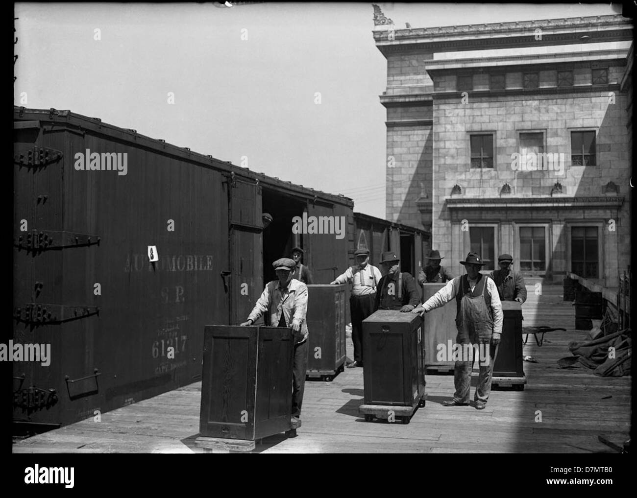 A historic image depicting a train and loading dock scene, possibly ...