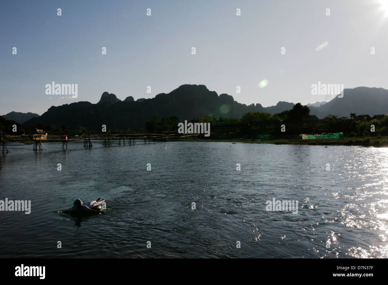 A tourist enjoys a ride in an inner tube on the Nam Song River in Vang ...