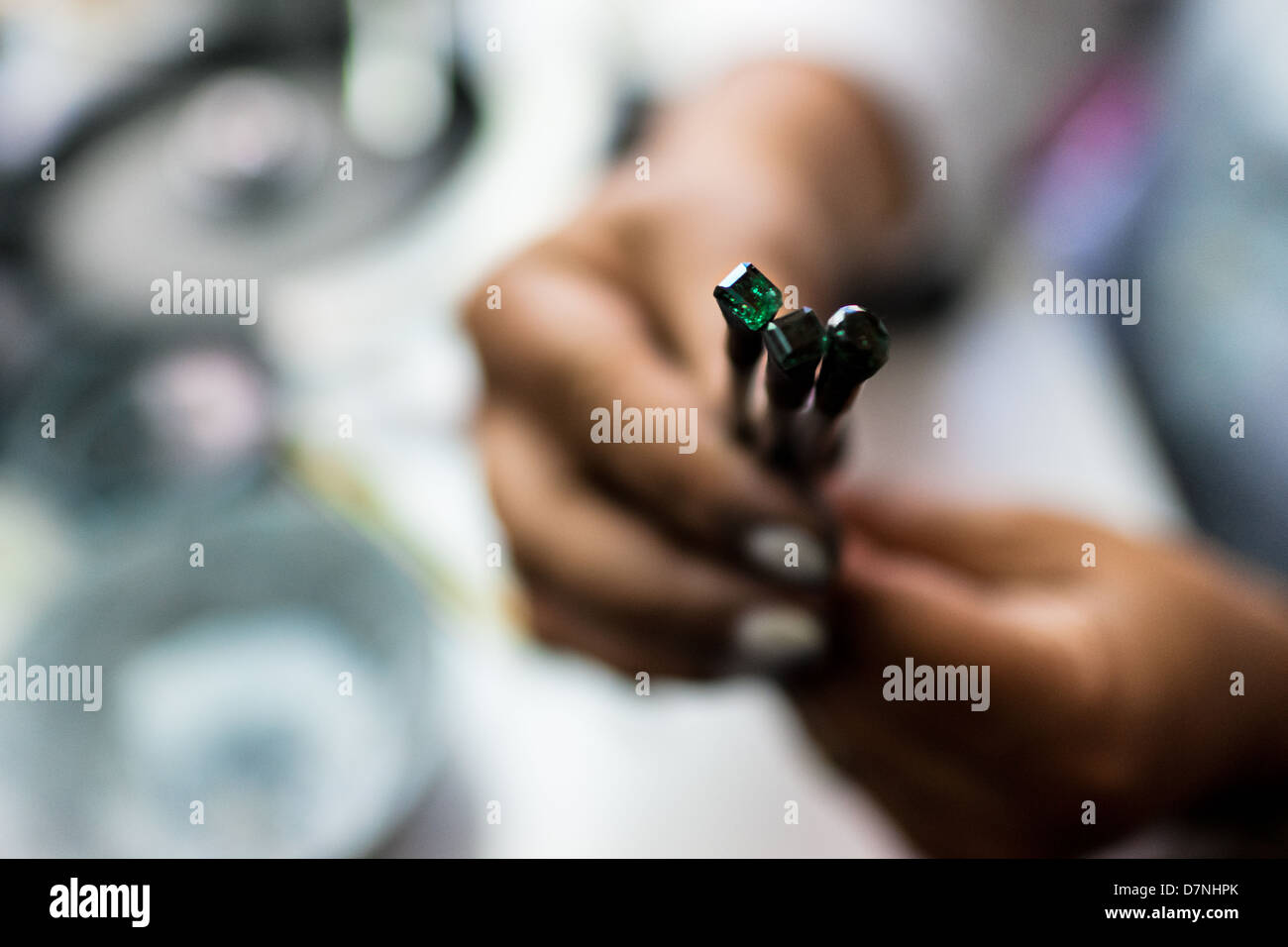 An emerald cutter shows a gemstone she is working on in a cutting and ...