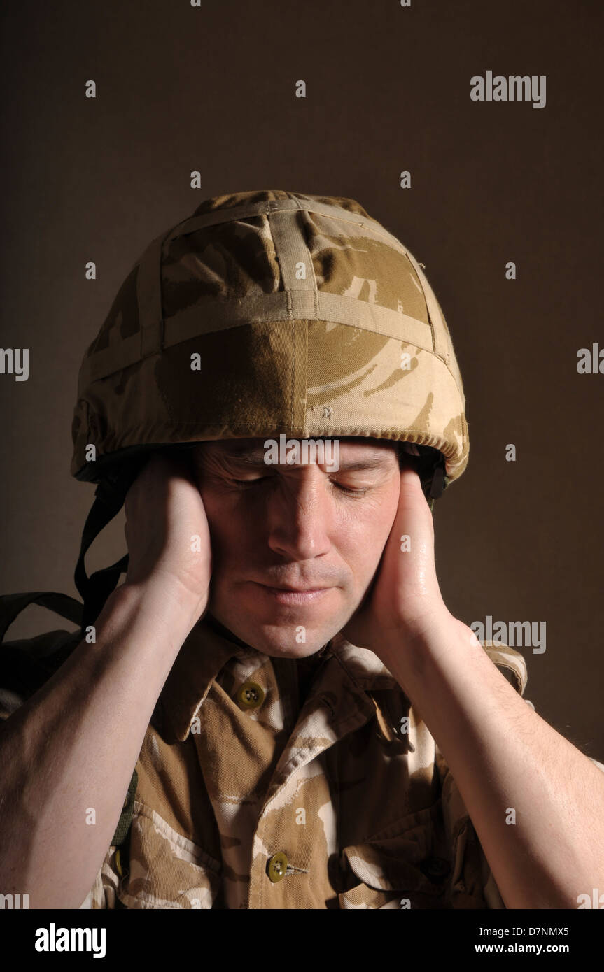 Soldier with his eyes closed and hands covering his ears. Soldier is ...