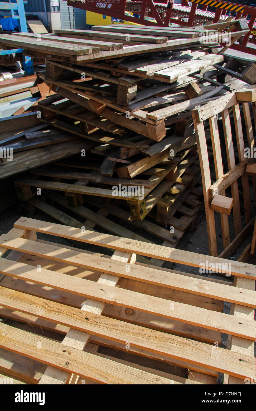 A stack of broken pallets with new pallets in front Stock Photo - Alamy