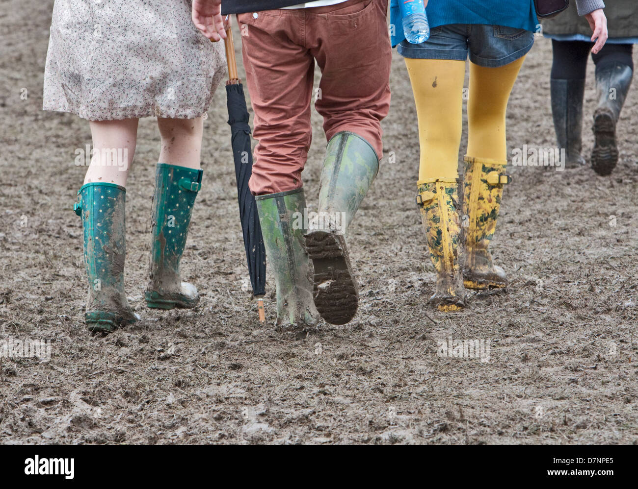 FESTIVALGOERS/ FESTIVAL GOERS WALKING THROUGH MUD AND PUDDLES IN WET ...