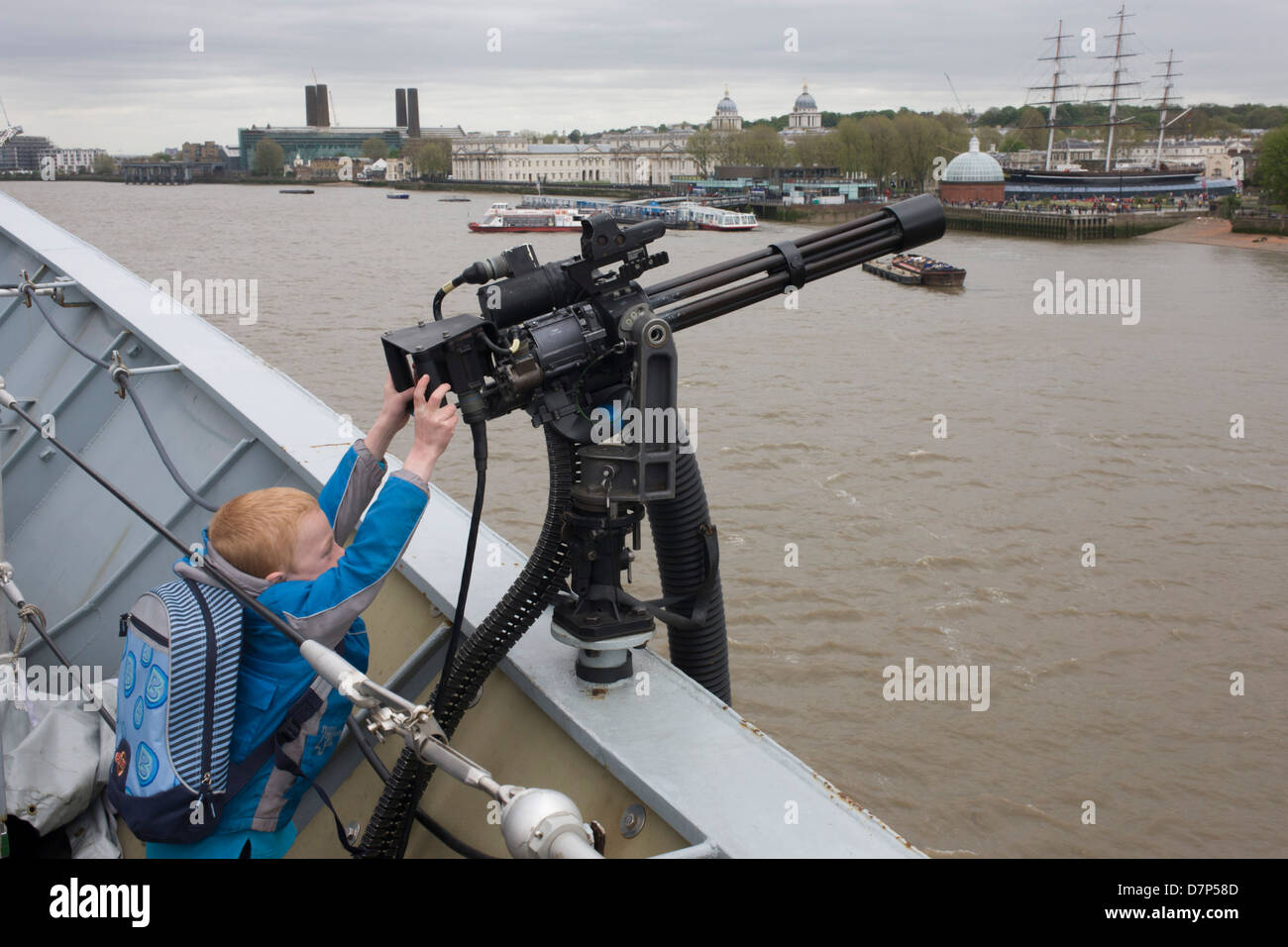 A young boy, too short to reach points a Minigun cannon from the top ...