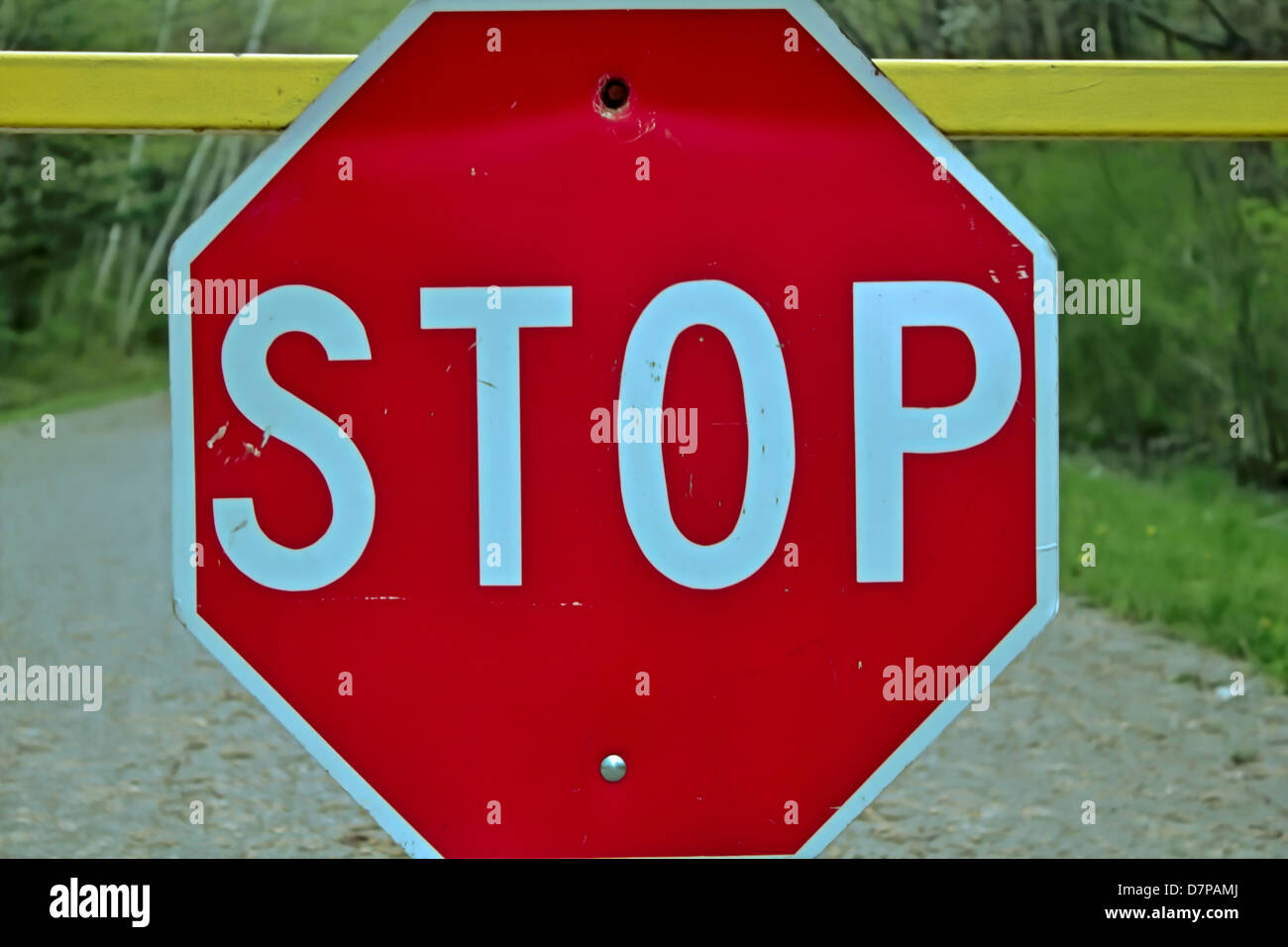 Stop! Stop sign suspended from yellow bar Stock Photo - Alamy