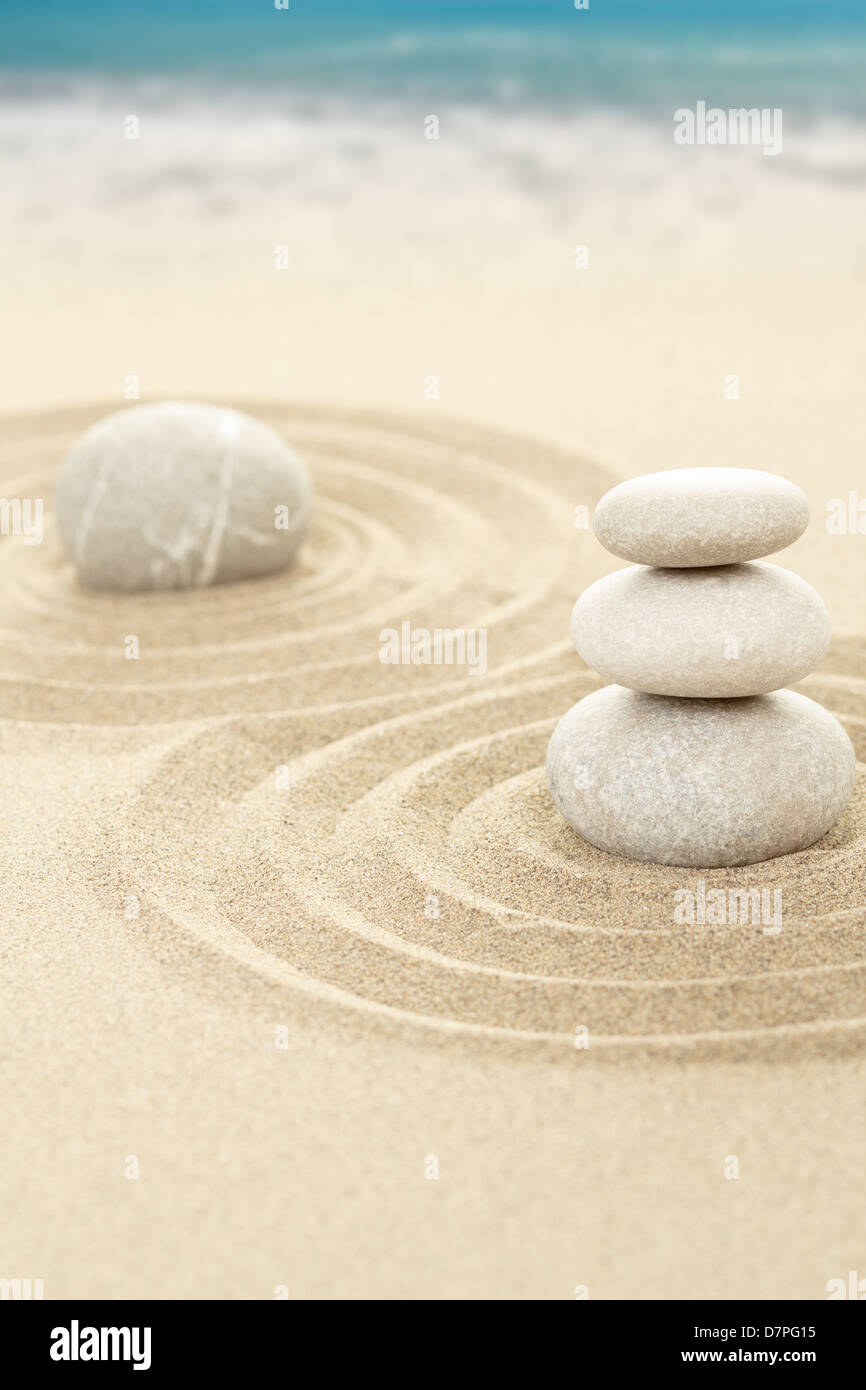Balance zen stones in sand with sea in background Stock Photo - Alamy