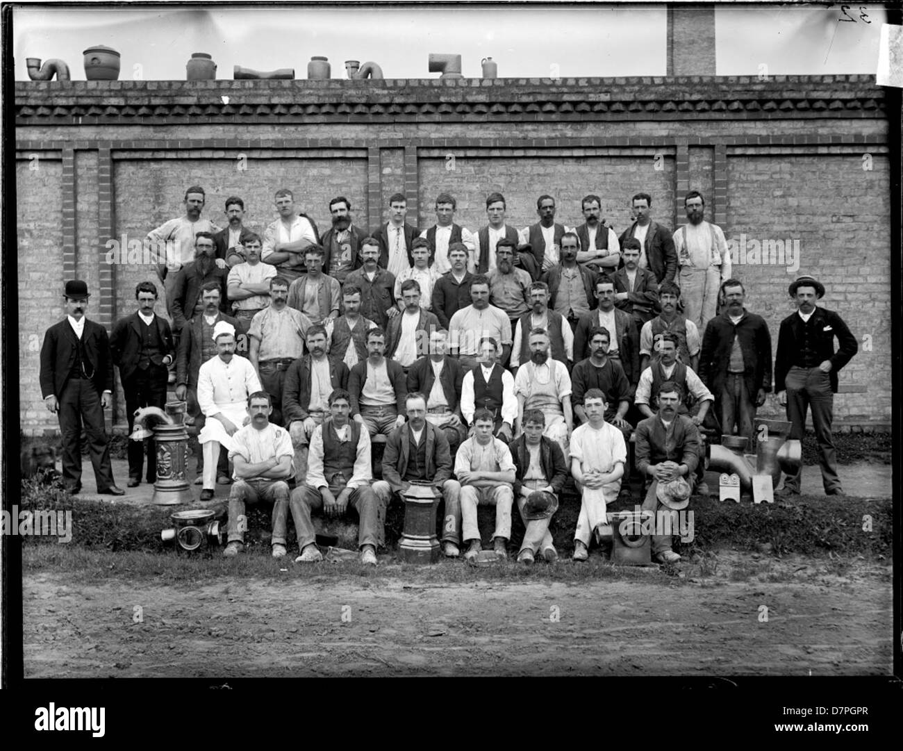 A historical photograph showing workers at an earthenware pipe and tile ...