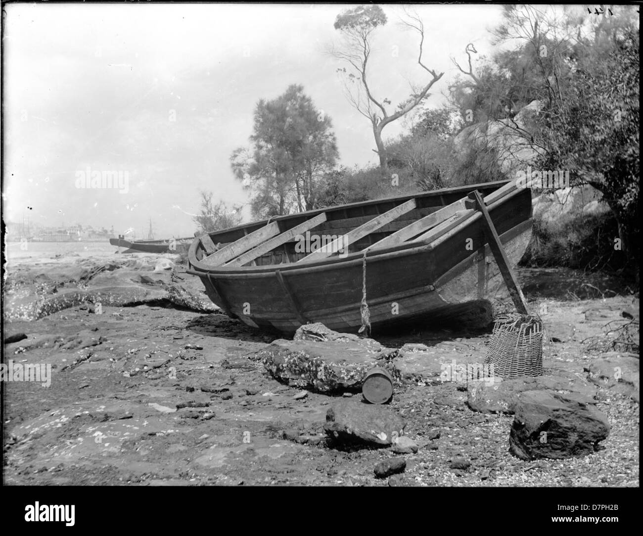This image depicts a rowing boat pulled ashore on a rock shelf ...
