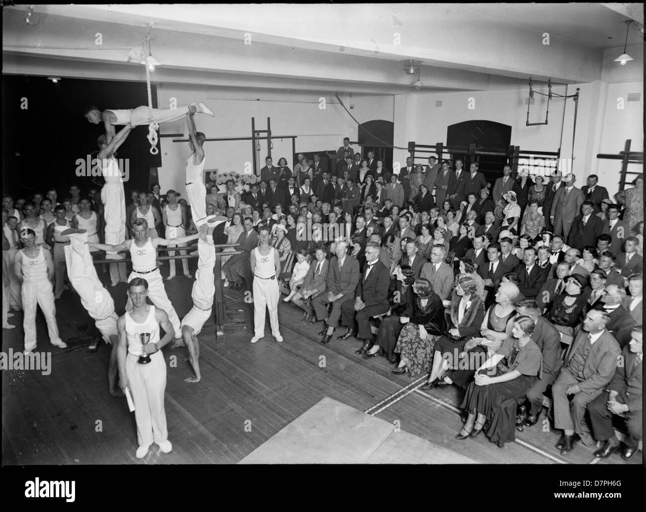 This image shows gymnasts performing for an audience in a hall ...