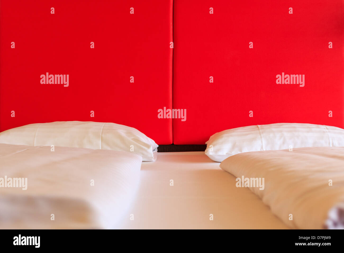 Double bed with separate sheets and a red leather wall Stock Photo - Alamy