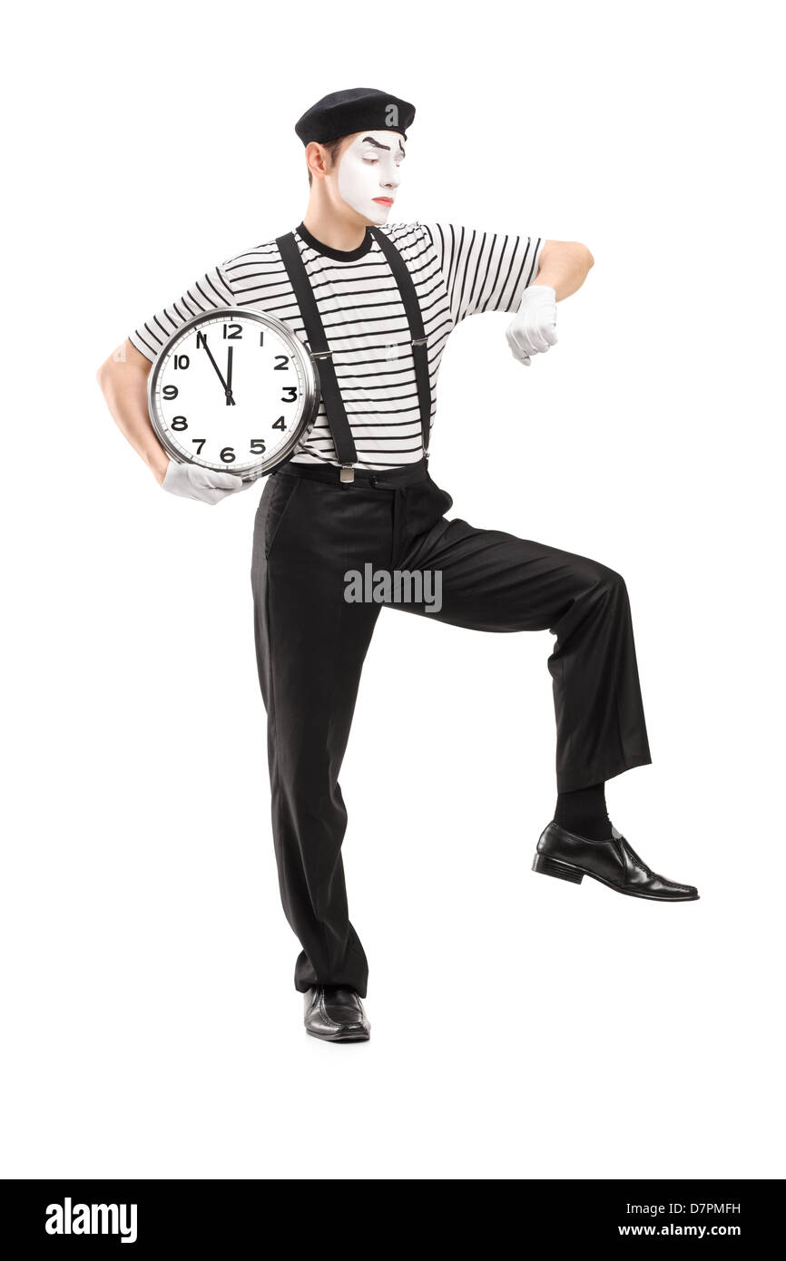 Full length portrait of a mime artist holding a clock and checking the ...