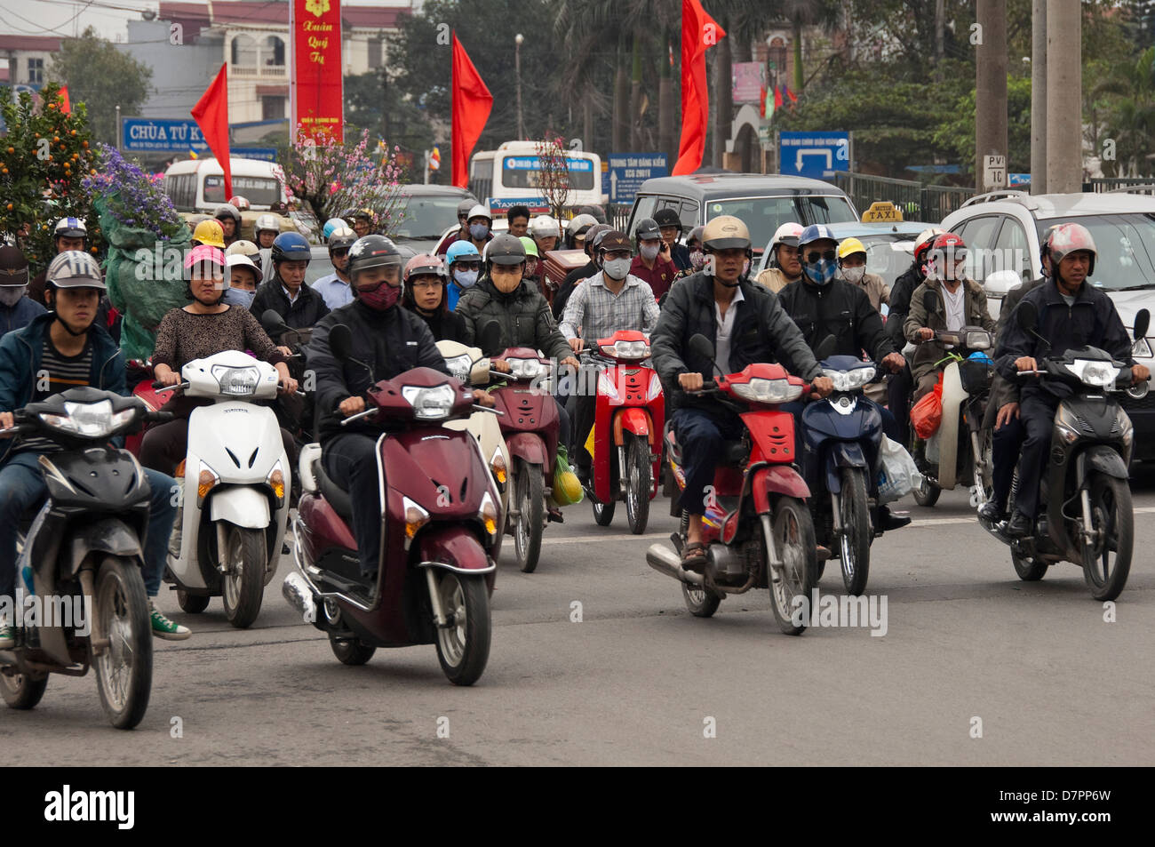 Horizontal street view of lots of mopeds laden with people and ...