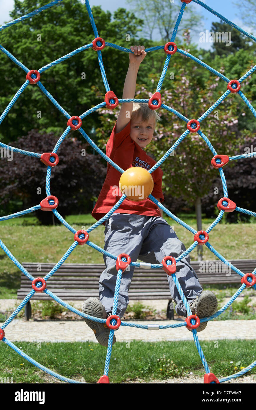 Young child blond boy climbing rope net in playground summer Stock ...