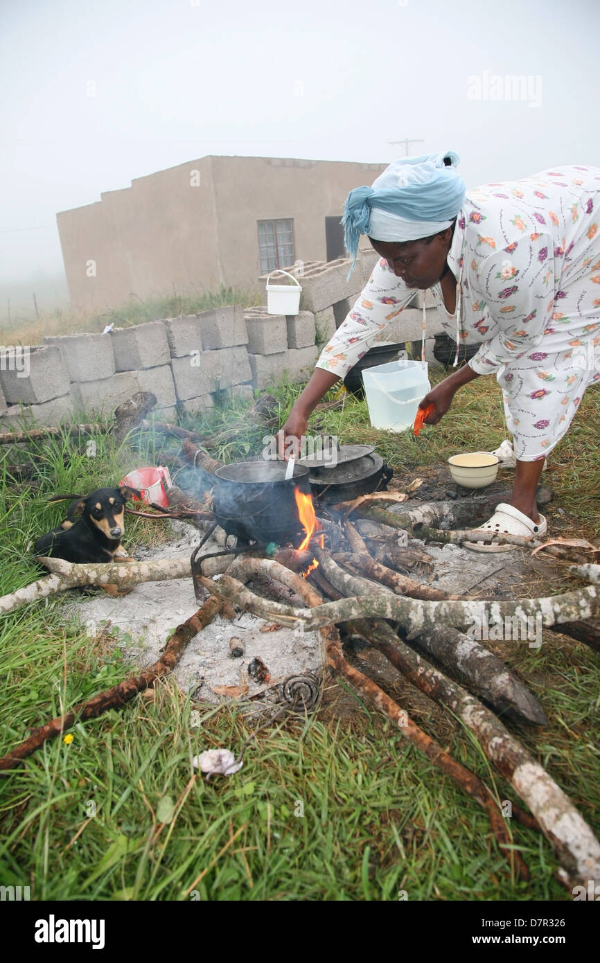 An African woman cooks outside on a wood fire as the mist rolls in ...