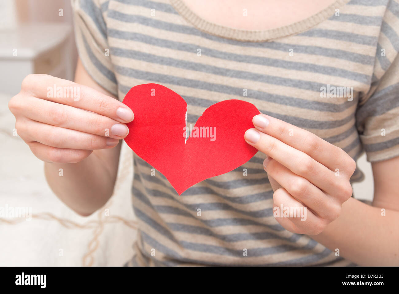 Break red heart in beautiful female hands (fingers) in bedroom ...