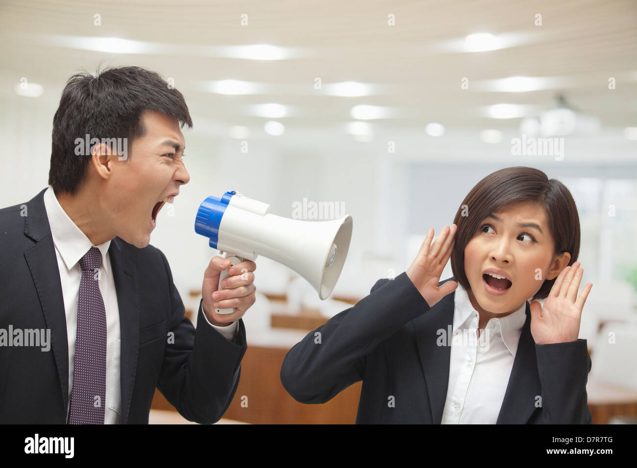 Businessman Talking into Megaphone by Businesswoman's Ear Stock Photo ...