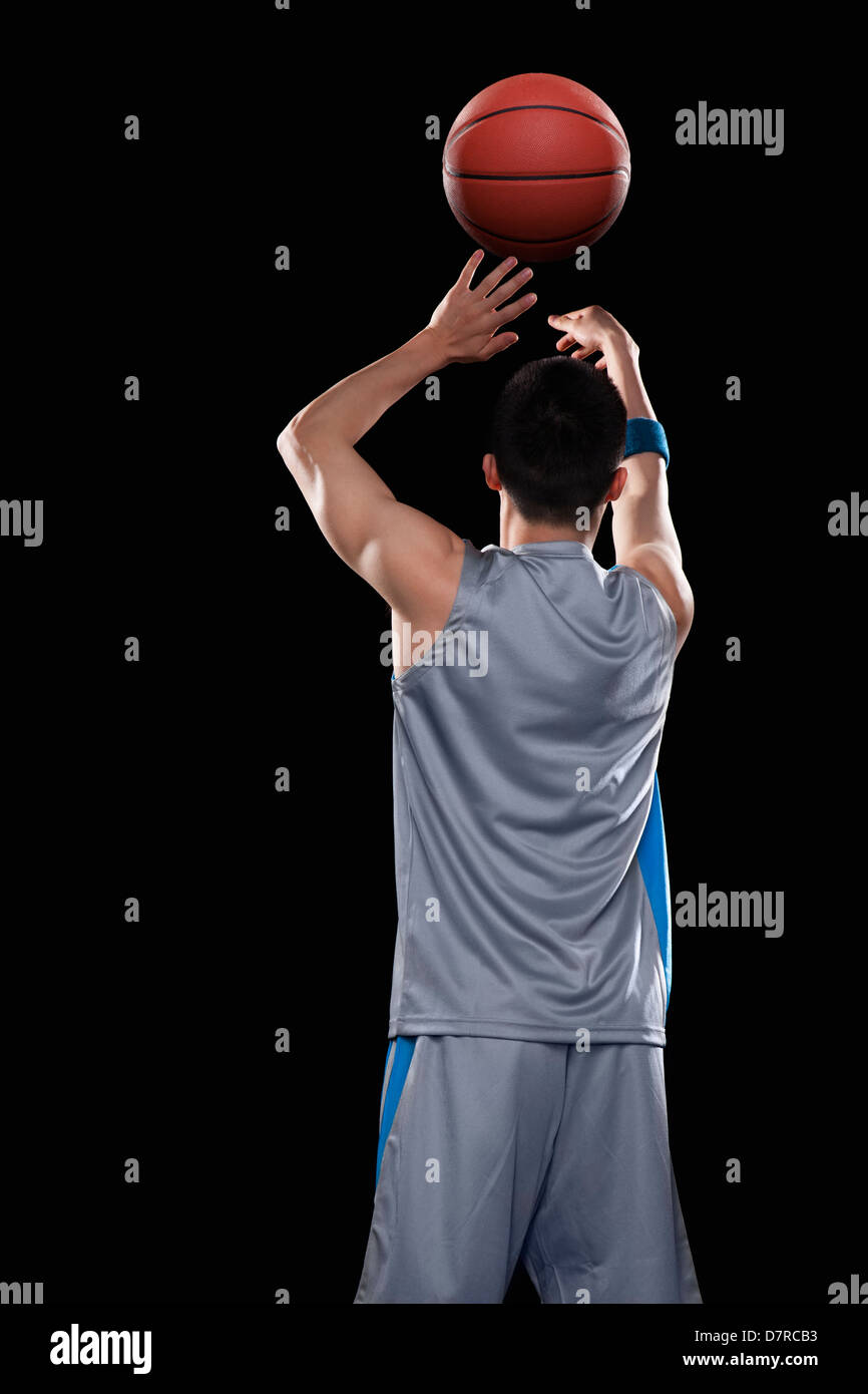 Basketball player throwing ball, black background Stock Photo - Alamy