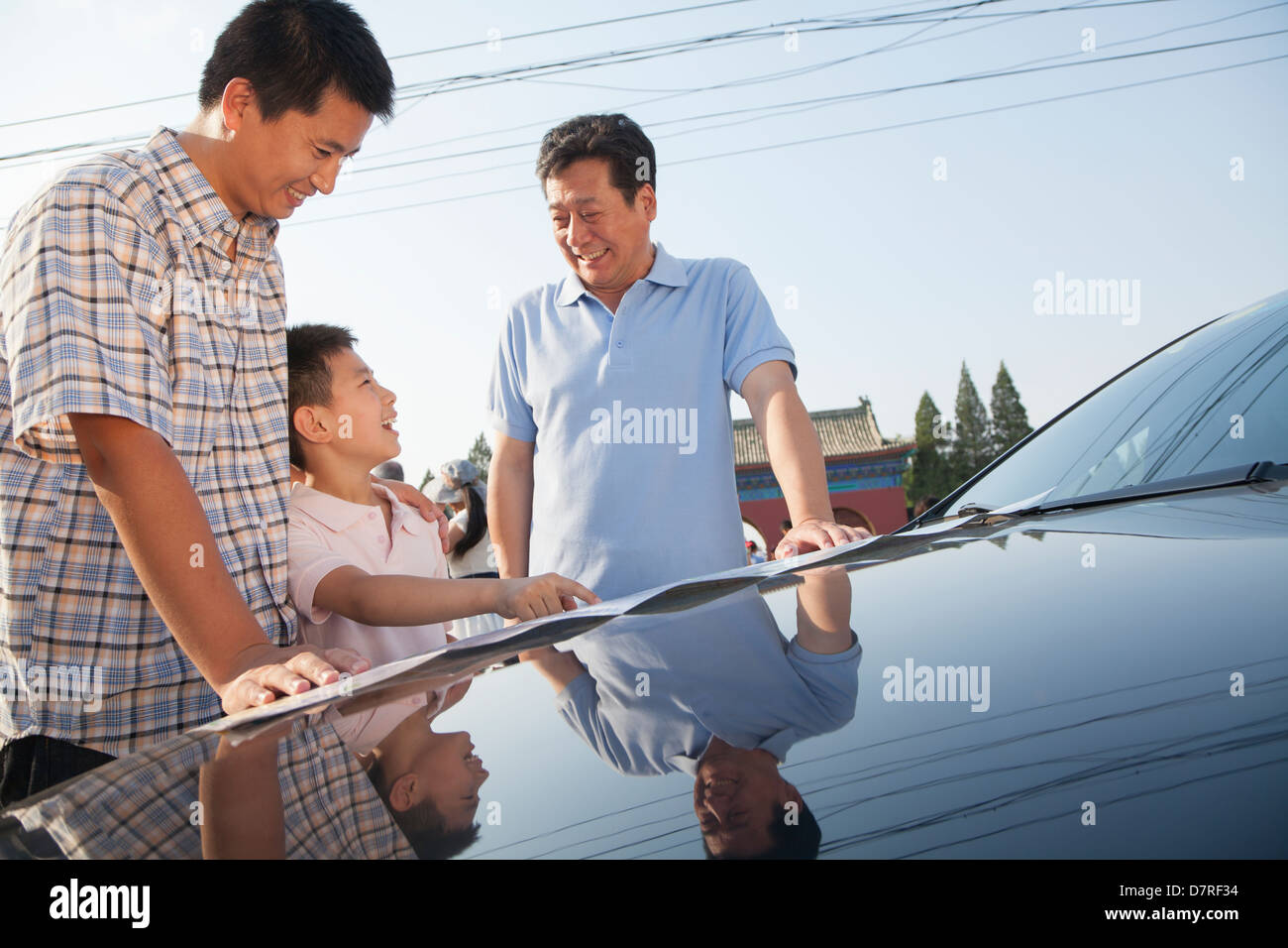 Family standing next to the car and looking at the map Stock Photo - Alamy