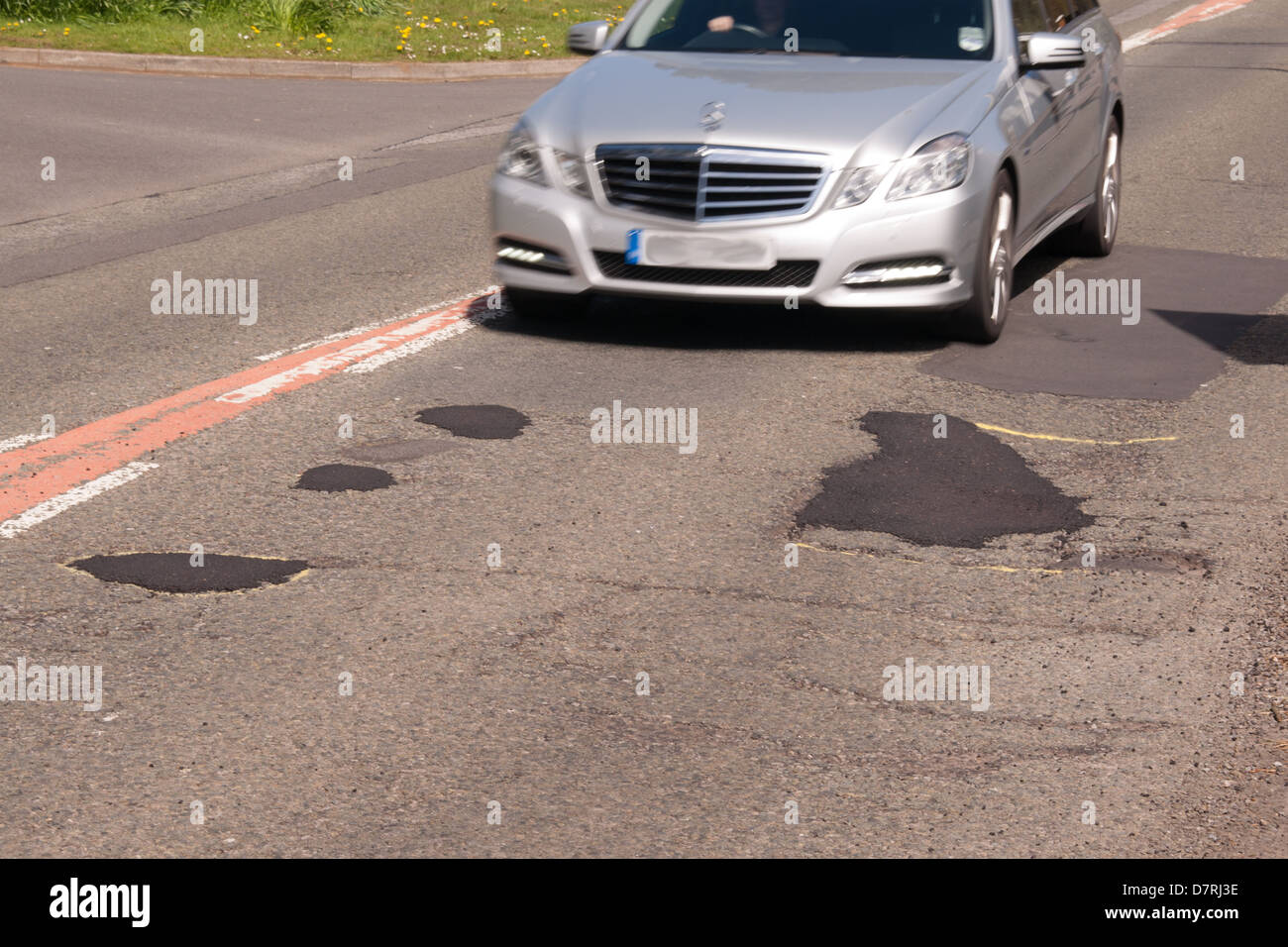 Car avoiding poorly repaired potholes in the road. Driver is crossing ...