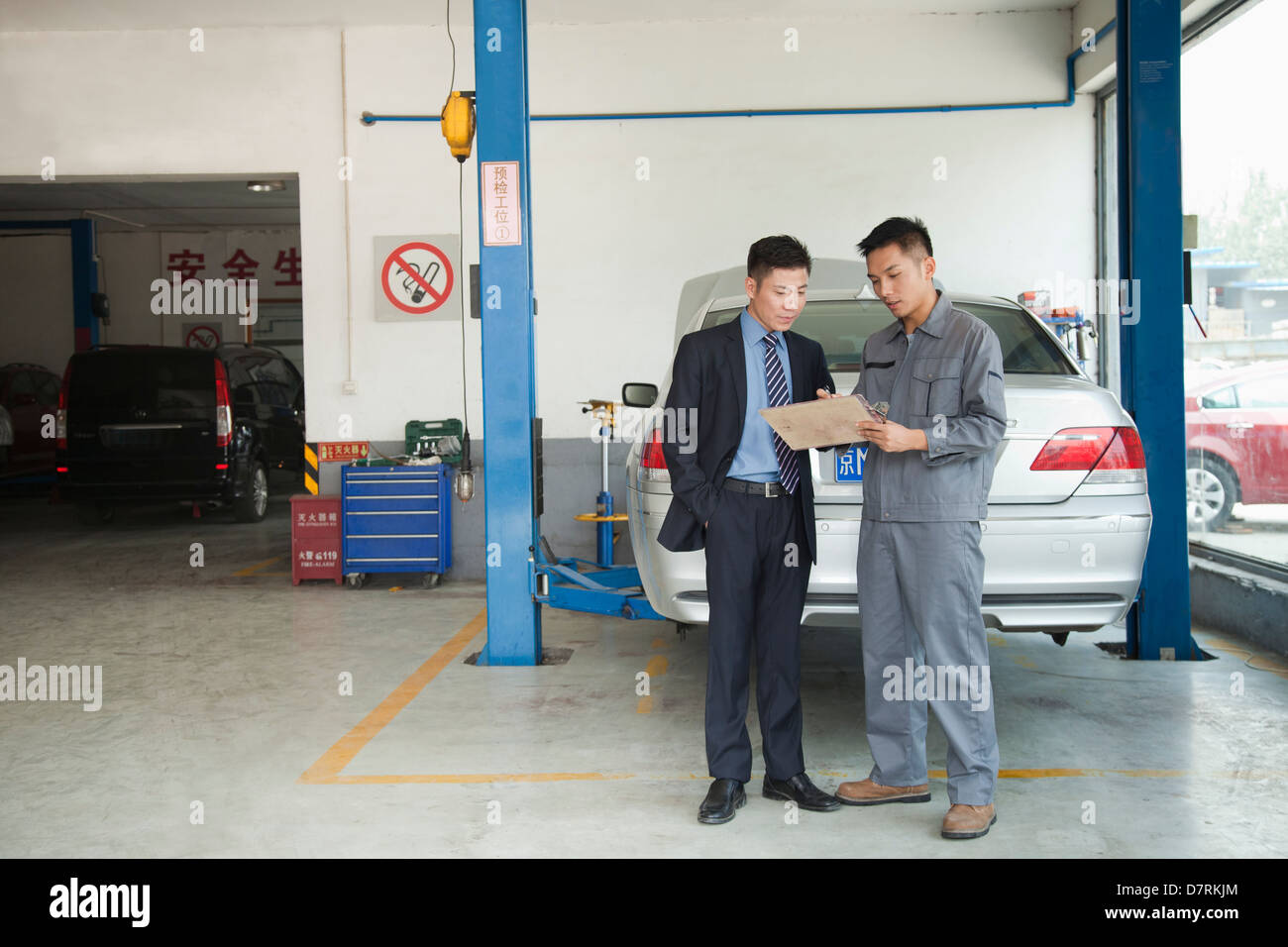 Garage Mechanic Explaining to Customer Stock Photo - Alamy