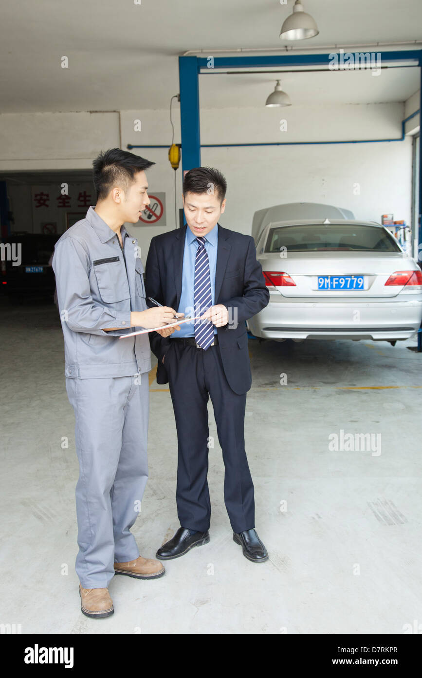 Garage Mechanic Explaining to Customer Stock Photo - Alamy