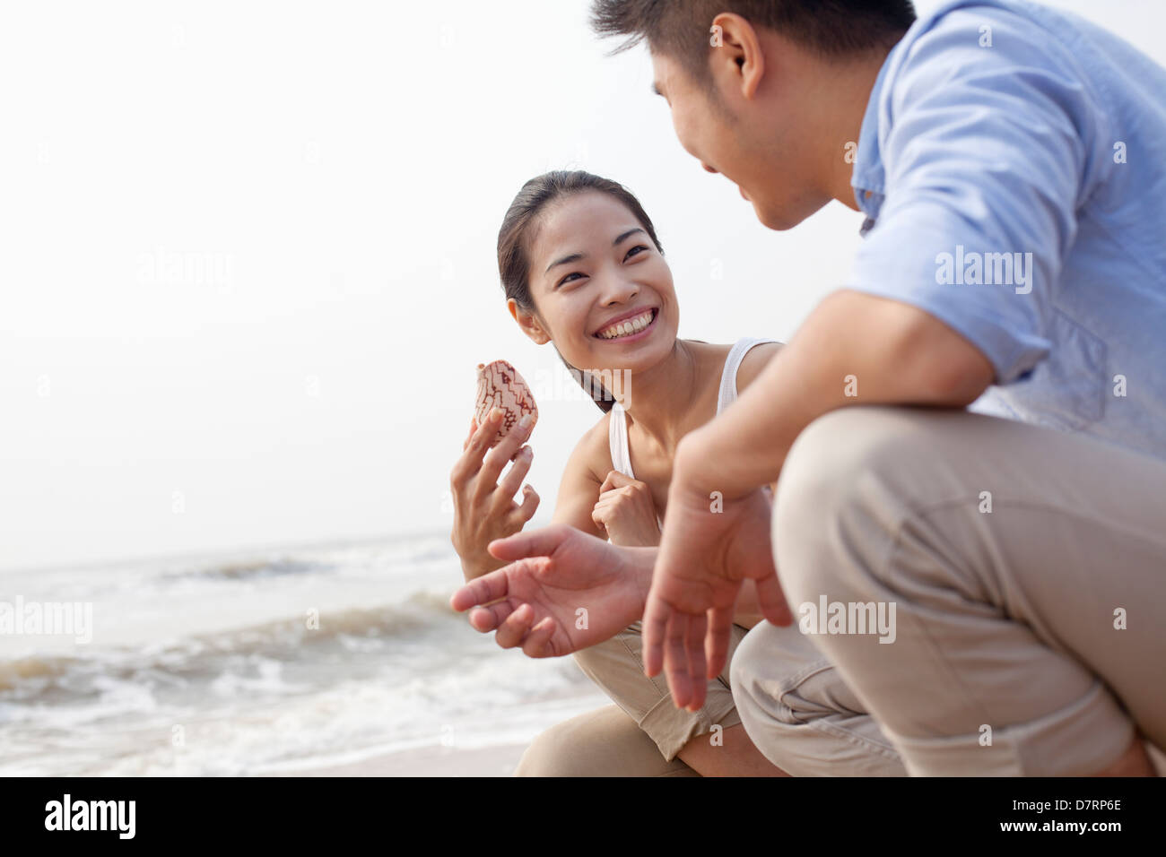 Young couple looking at seashell at the waters edge, China Stock Photo ...