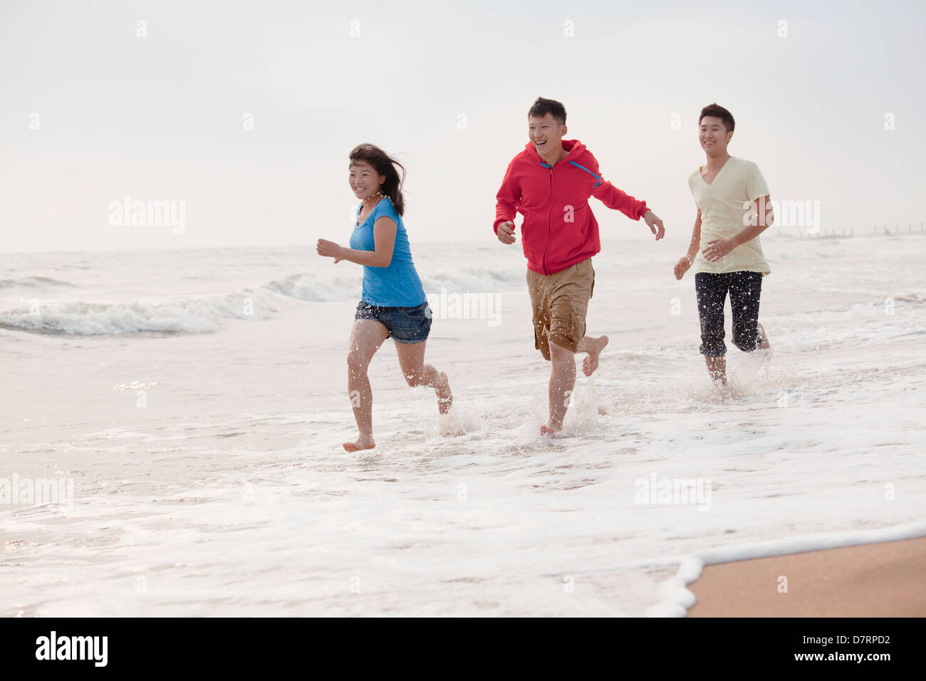 Three friends running on the beach by the waters edge, China Stock ...