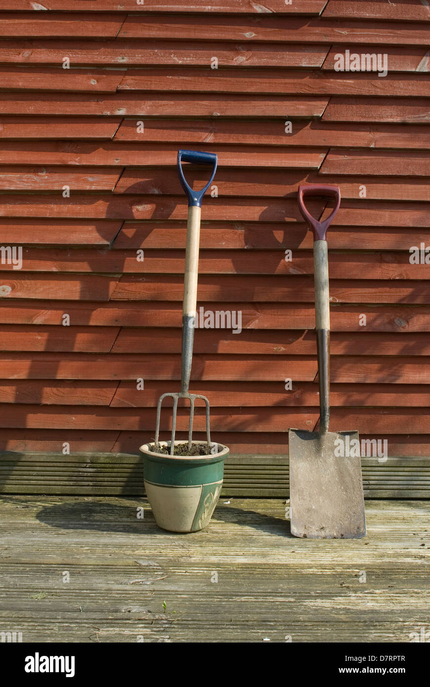 garden fork and spade leaning on fence Stock Photo - Alamy
