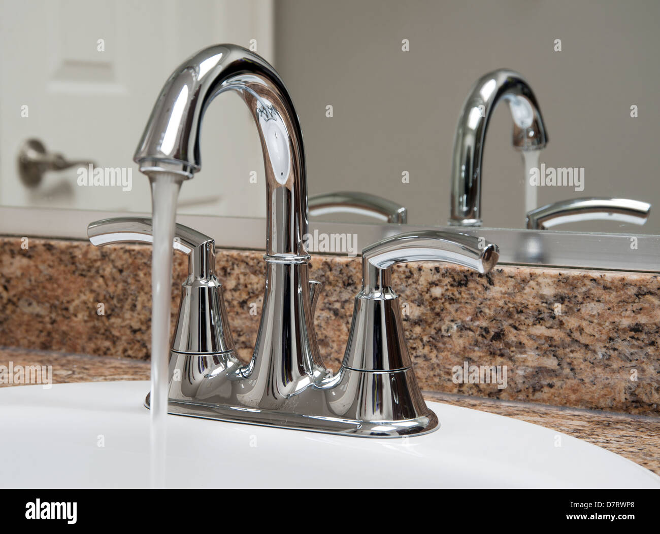 Bathroom taps with water running into sink Stock Photo - Alamy