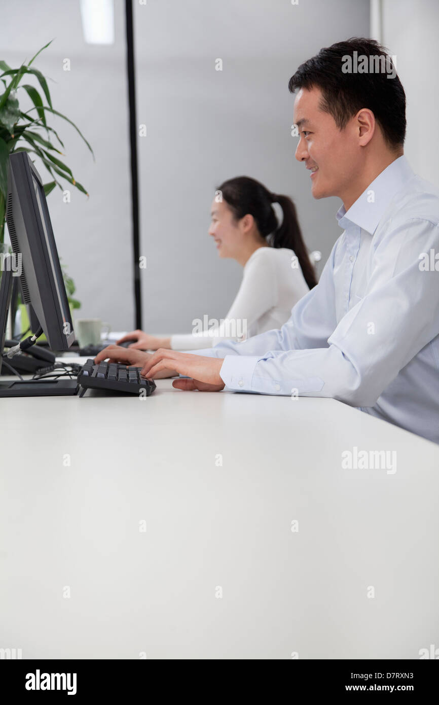 Happy coworkers working on their computers in the office Stock Photo ...