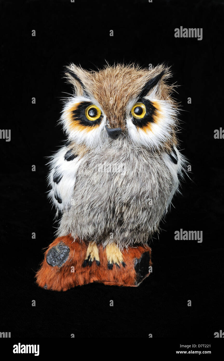 Owl standing on log ornament made from real fur against a black ...