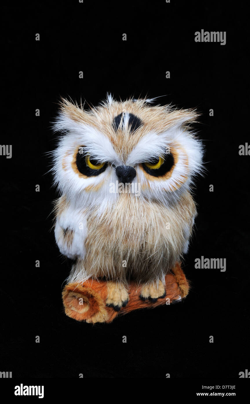 Owl standing on log ornament made from real fur against a black ...