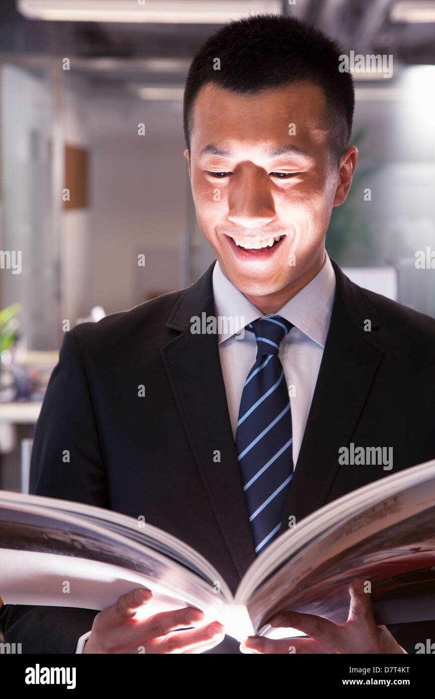 Young smiling businessman reading a book Stock Photo - Alamy