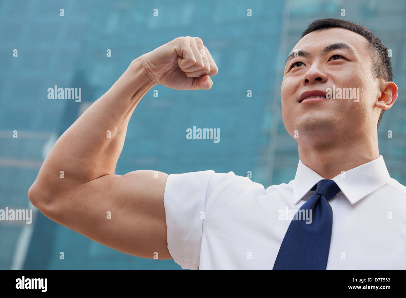 Portrait of young businessman flexing muscle outdoors Stock Photo - Alamy