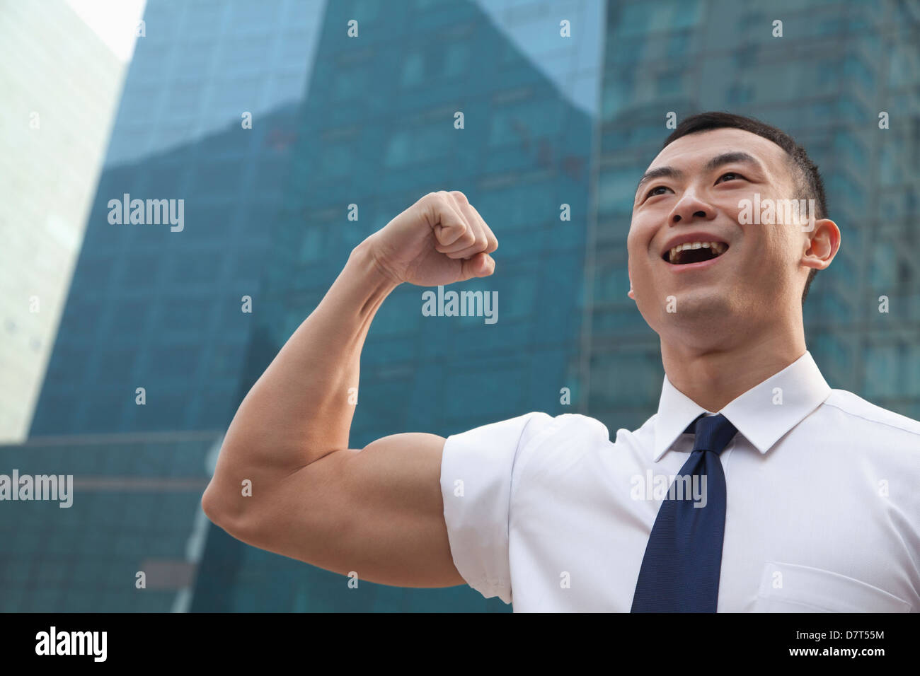 Portrait of young businessman flexing muscle outdoors Stock Photo - Alamy
